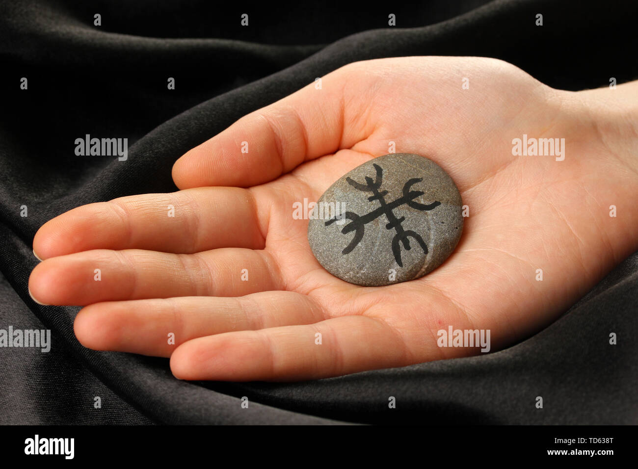 Fortune telling with symbols on stone in hand on black fabric ...