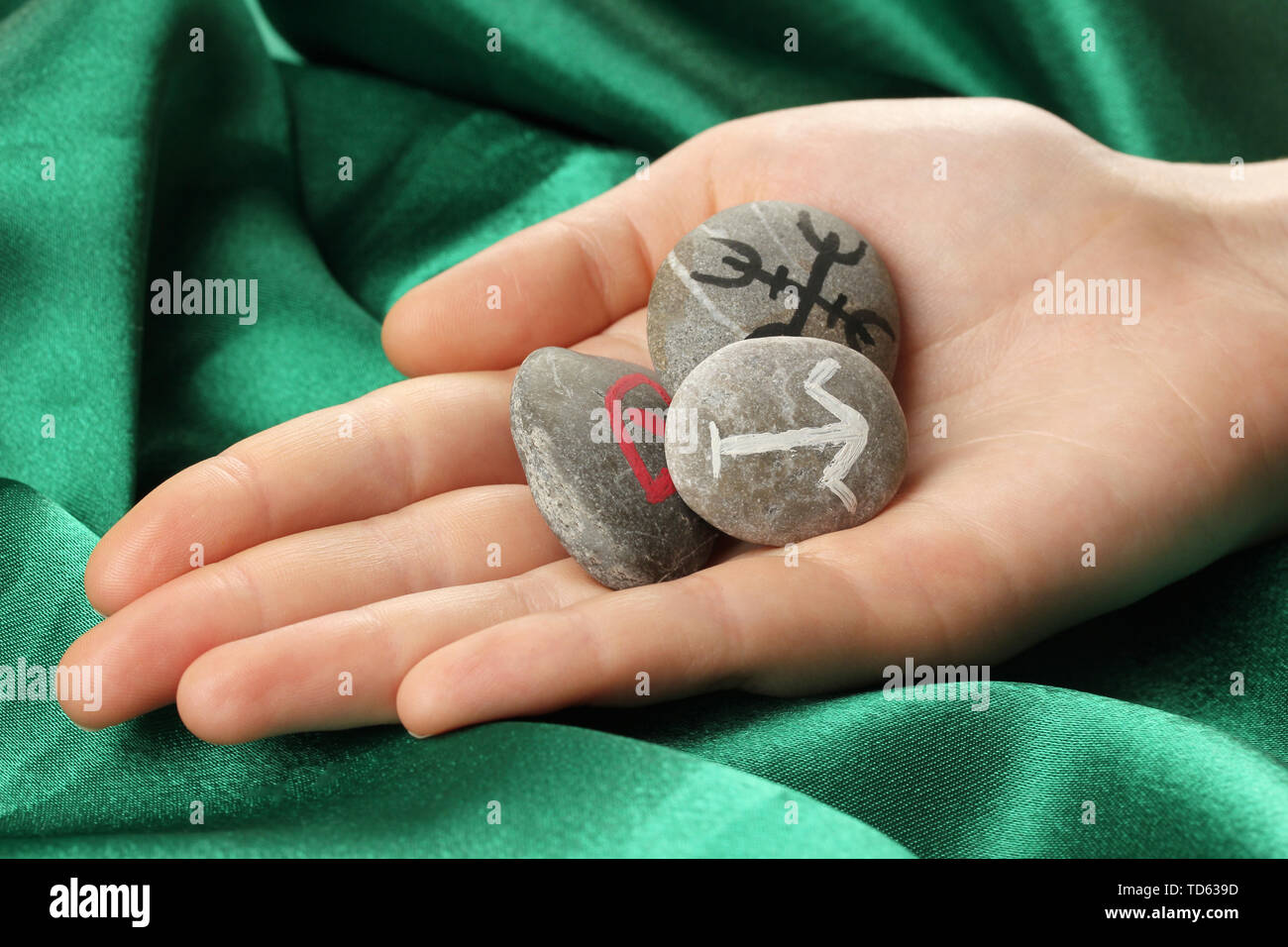 Fortune telling with symbols on stone in hand on green fabric ...