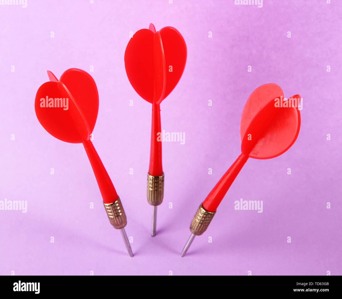Darts on purple background Stock Photo - Alamy