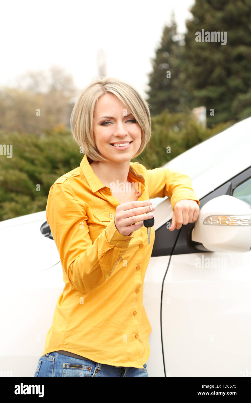 Portrait of happy beautiful woman with car keys, standing near the car ...