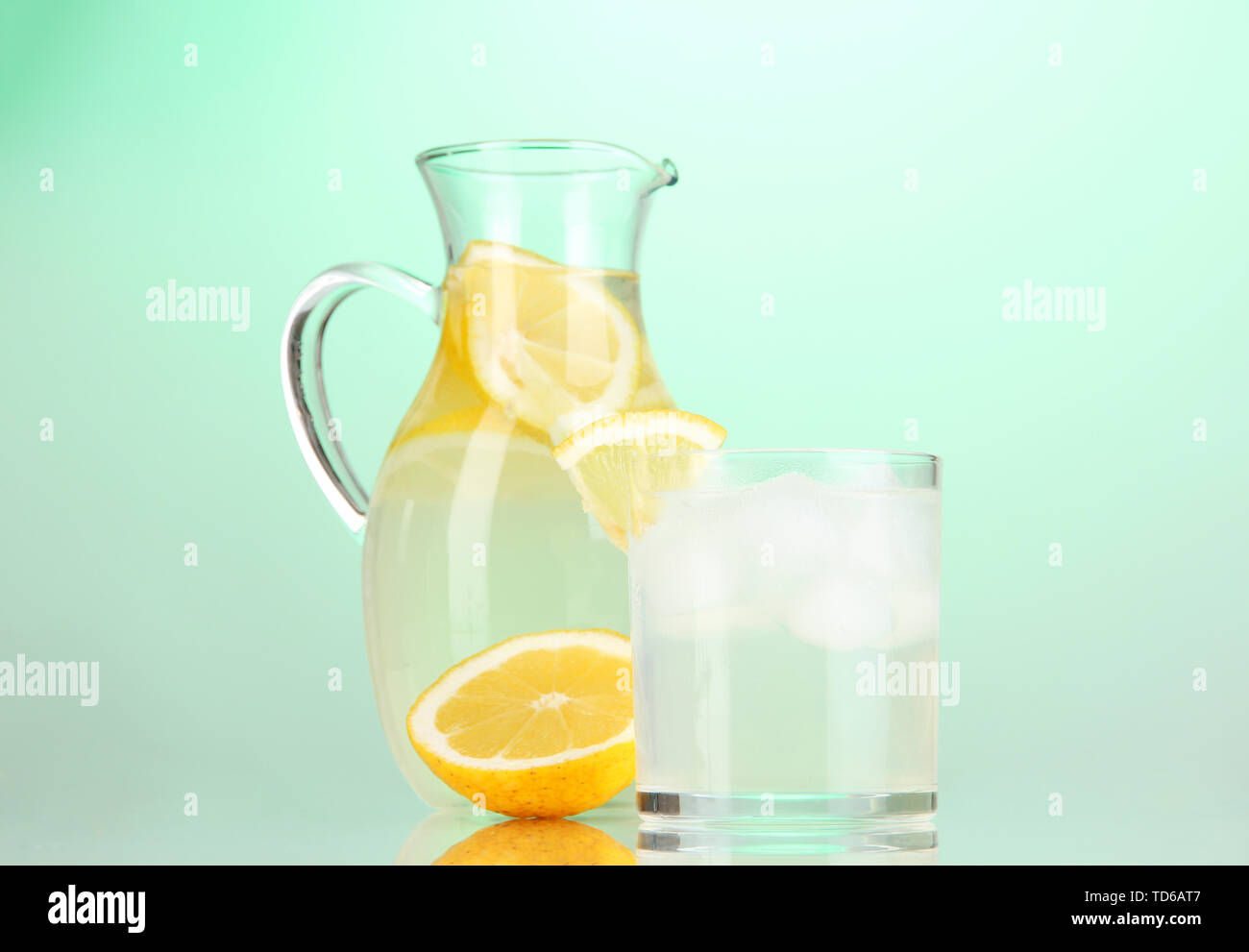 Lemonade in pitcher and glass on green background Stock Photo - Alamy