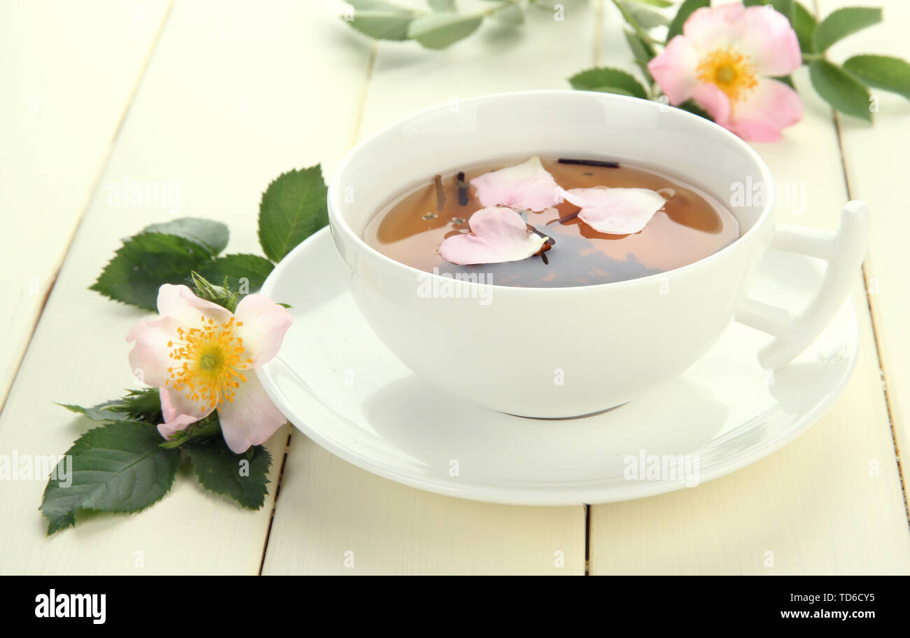 Cup of herbal tea with hip rose flowers on white wooden table Stock ...