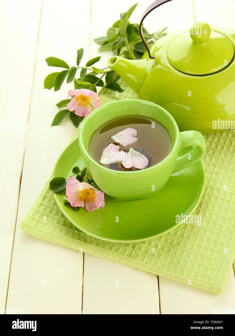 Cup and teapot of herbal tea with hip rose flowers on white wooden ...