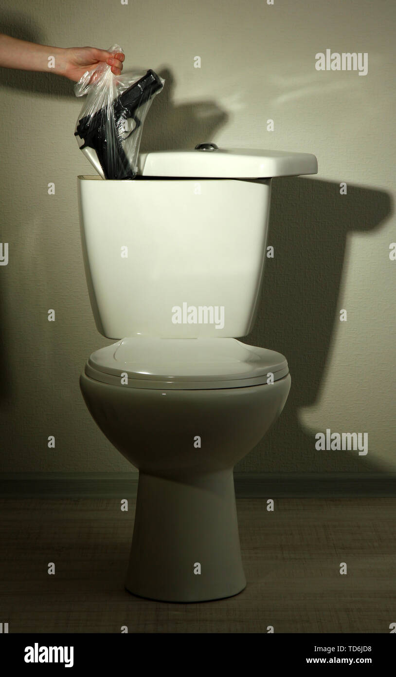 Hand hides gun in toilet tank in a bathroom Stock Photo - Alamy