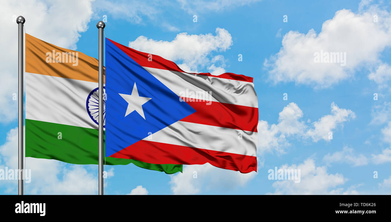 India and Puerto Rico flag waving in the wind against white cloudy blue ...