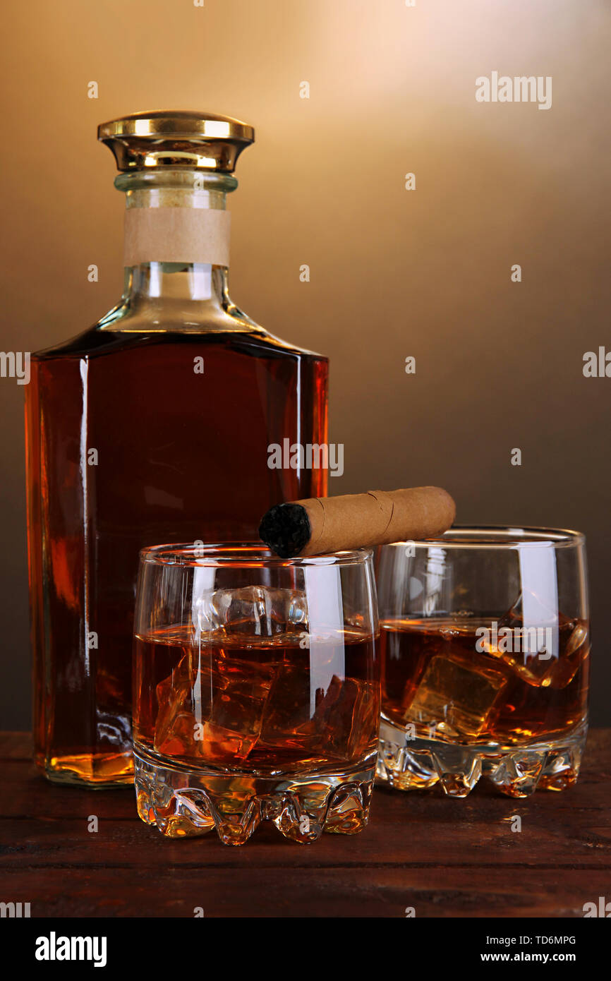 Brandy with ice on wooden table on brown background Stock Photo - Alamy