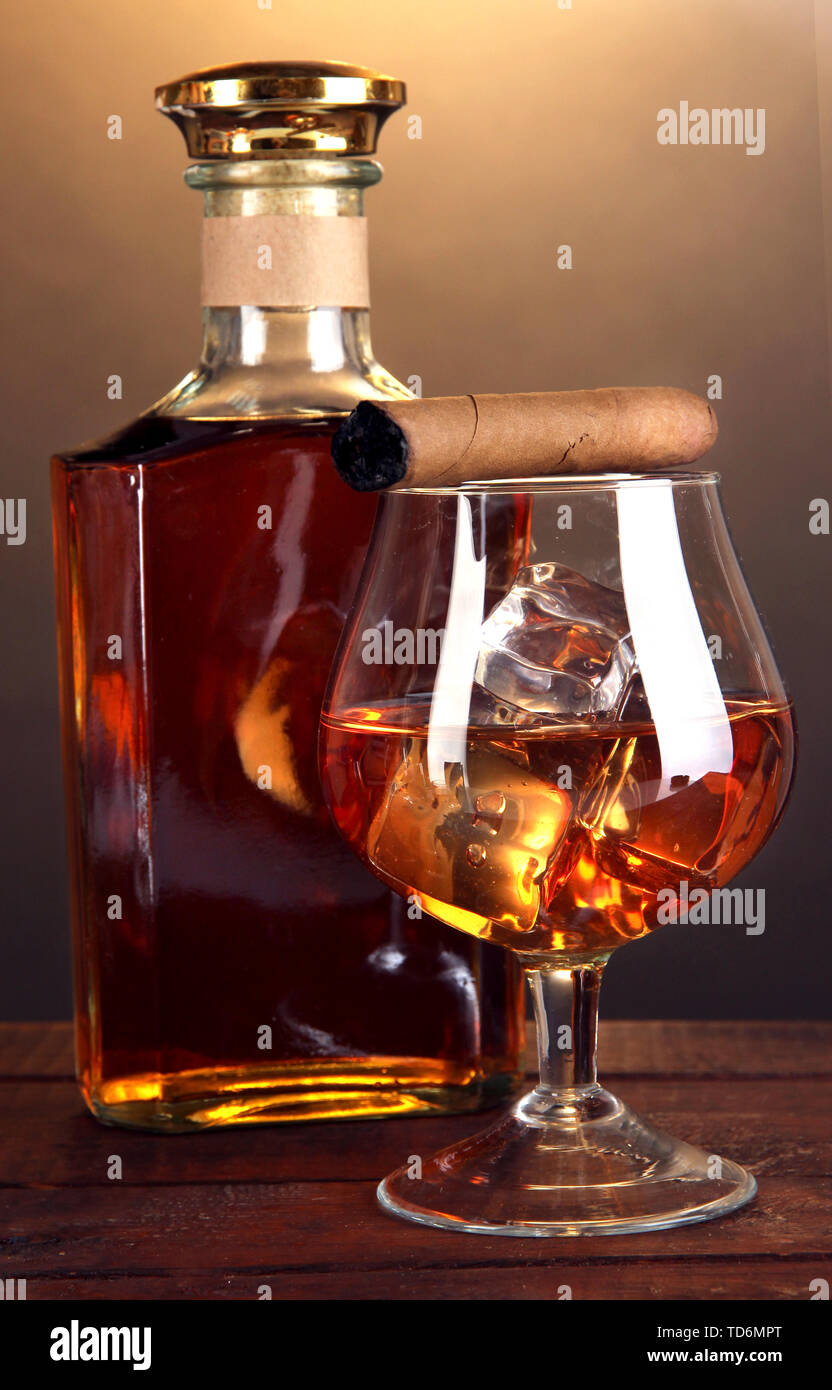 Brandy with ice on wooden table on brown background Stock Photo - Alamy