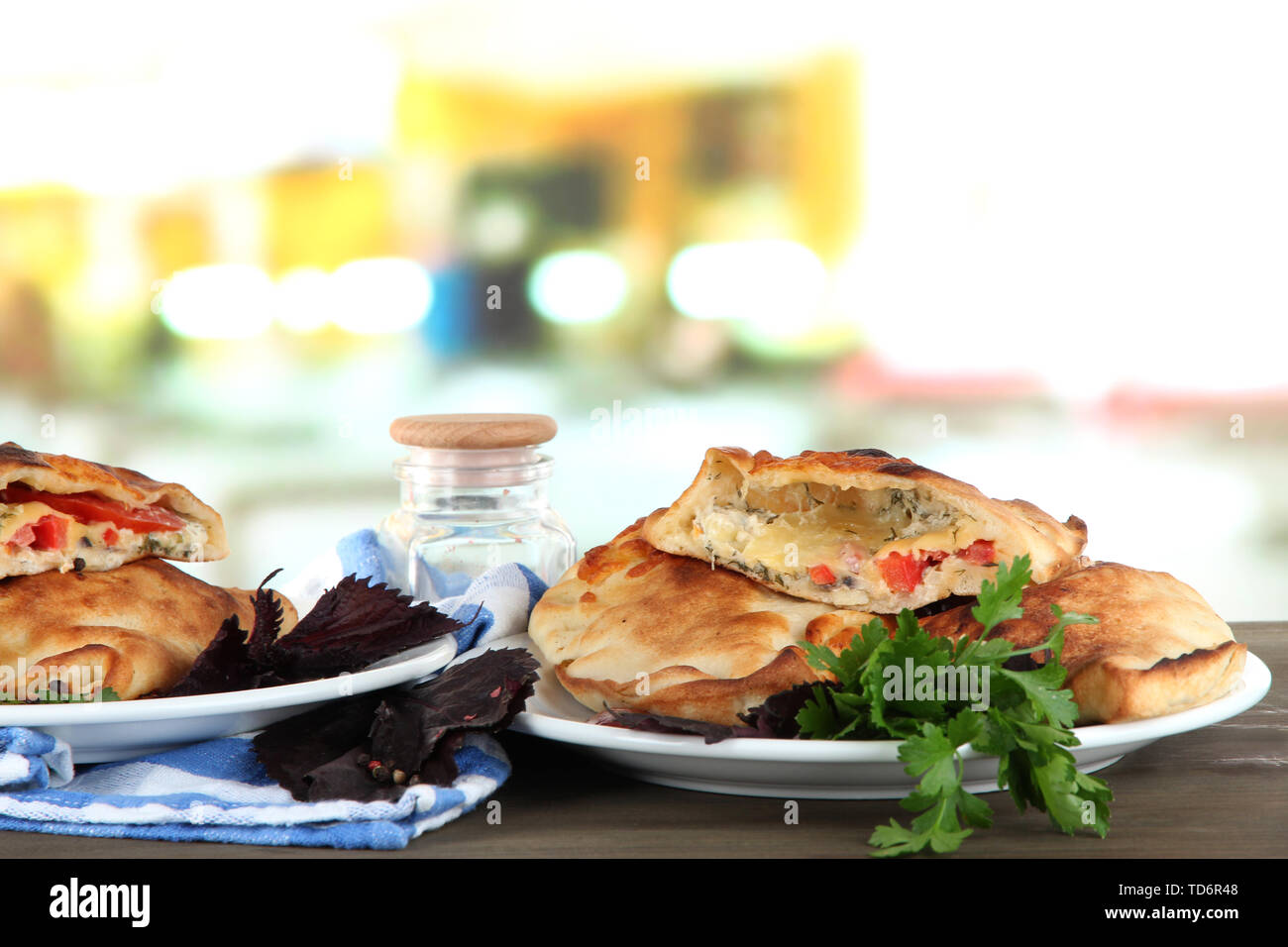 Pizza calzones on plates on table on room background Stock Photo - Alamy
