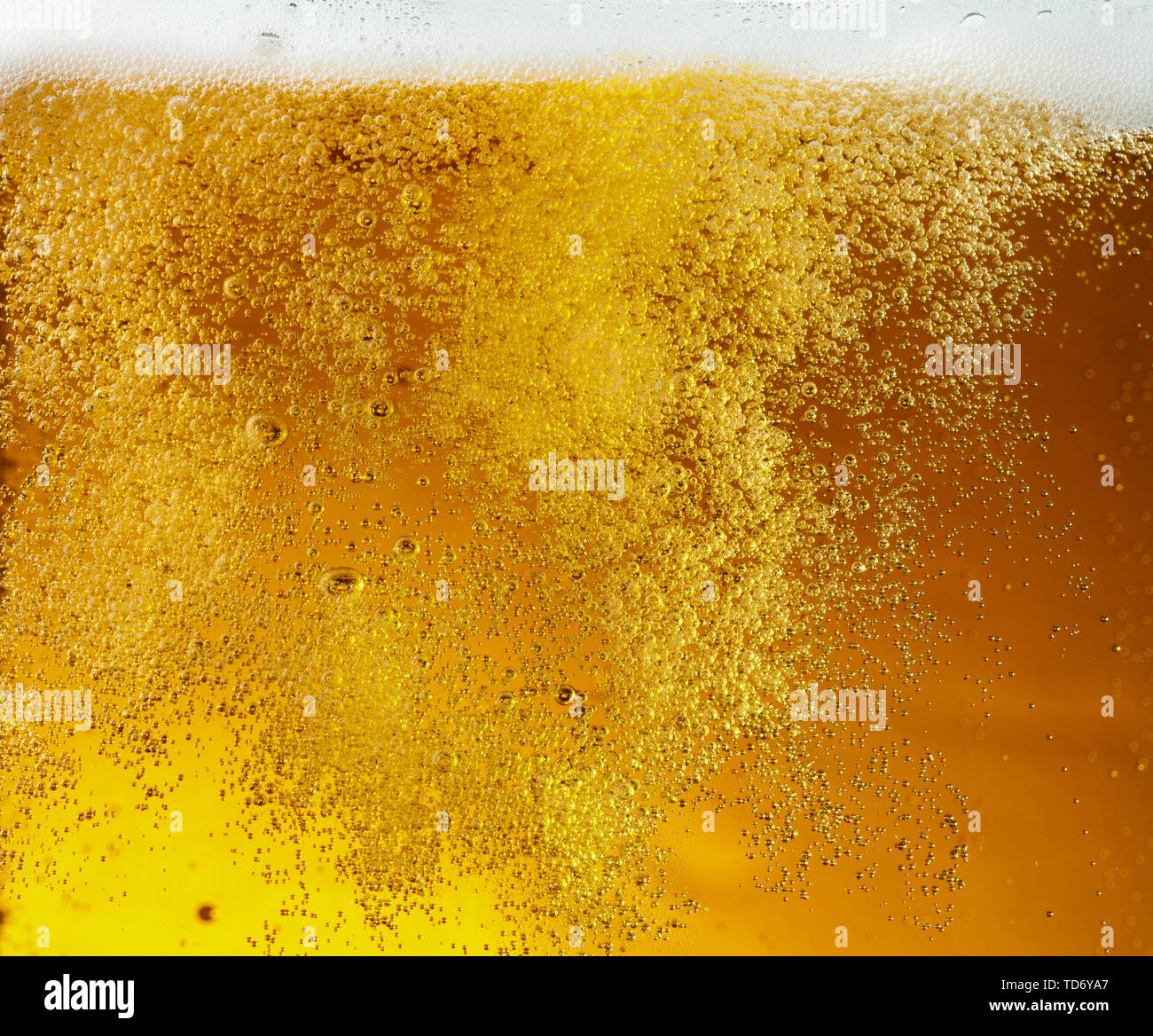 Close up view of floating bubbles in light golden colored beer ...