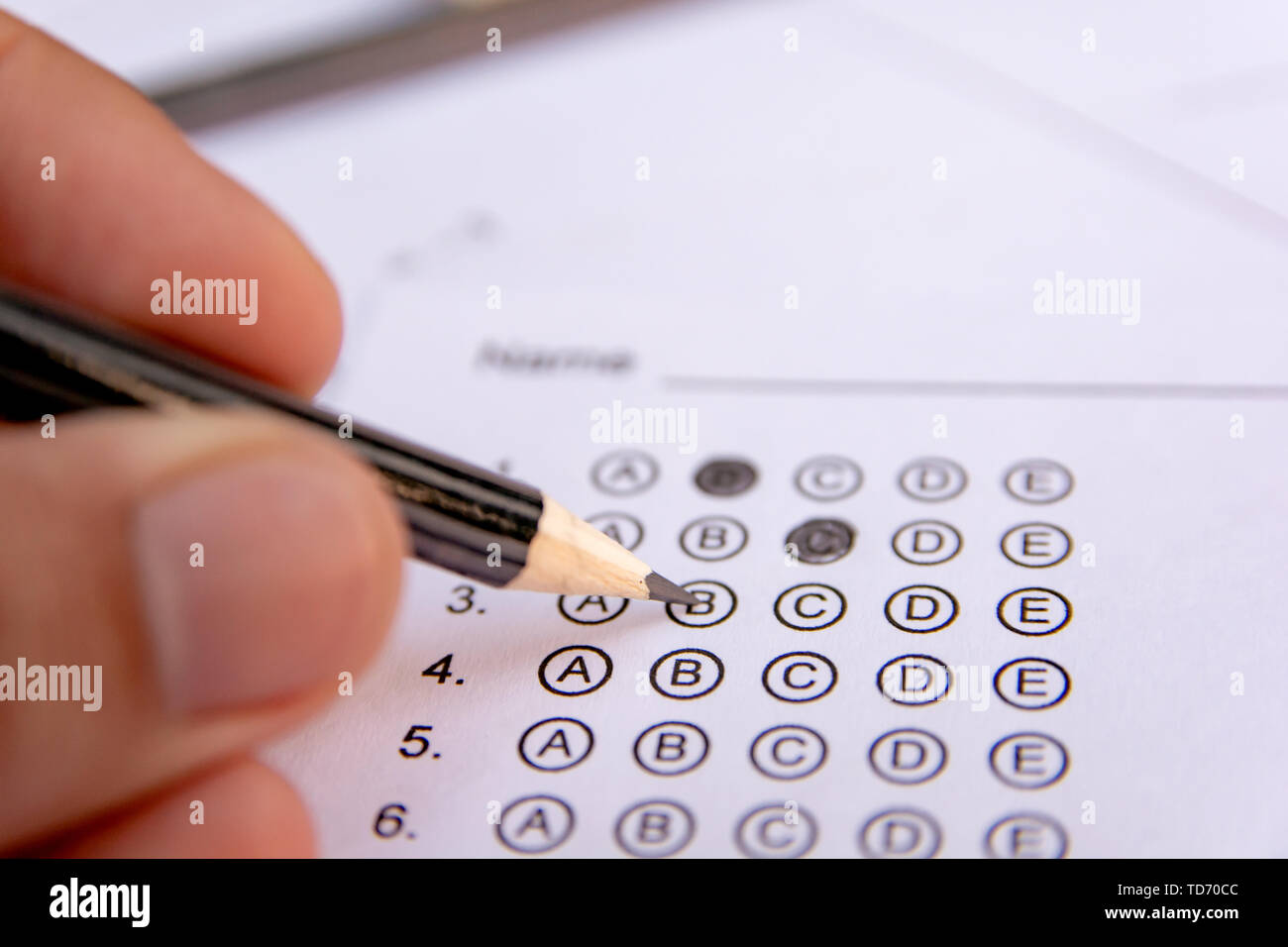 Students hand holding pencil writing selected choice on answer sheets ...
