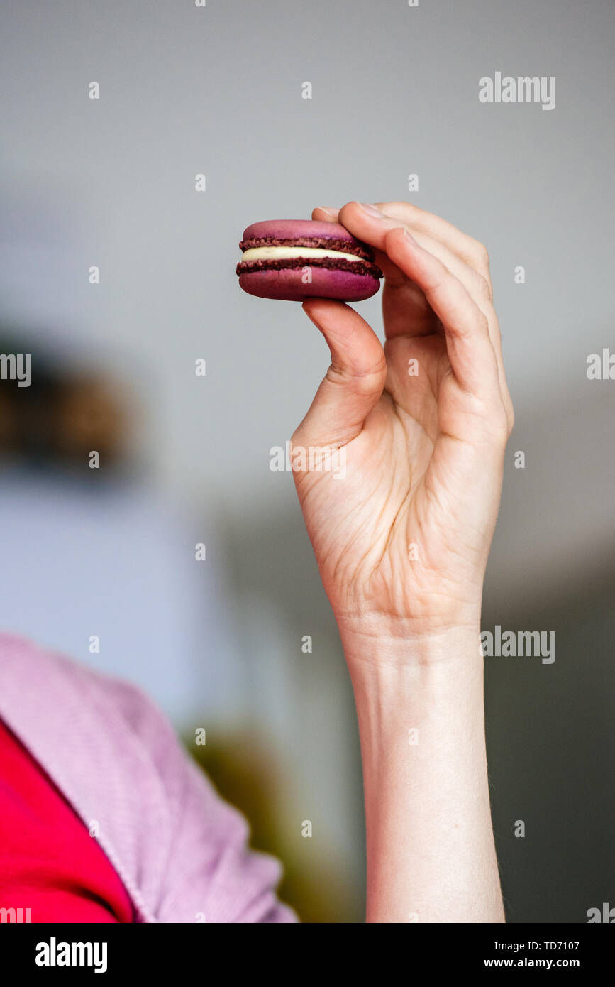 Young happy French woman showing delicious French sweet macaron made ...