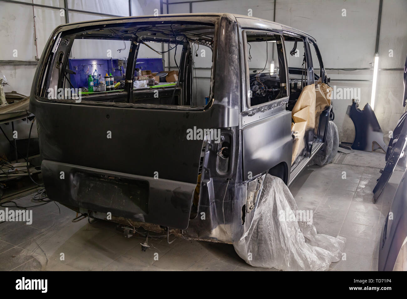 A large black matte car without windows is covered in paper and ...