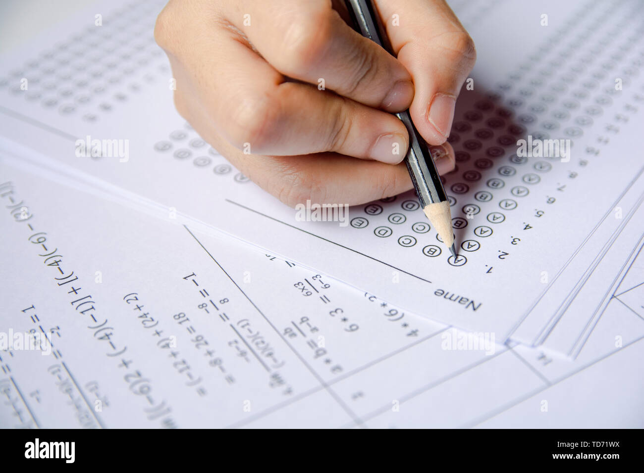 Students hand holding pencil writing selected choice on answer sheets ...