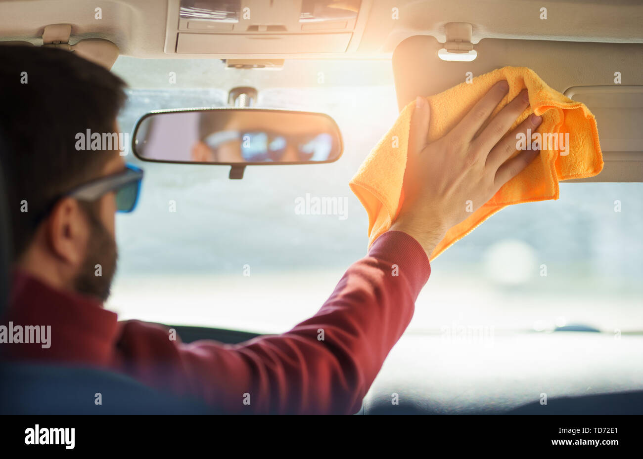 Image from back of brunet in sunglasses washing mirror sitting in car ...