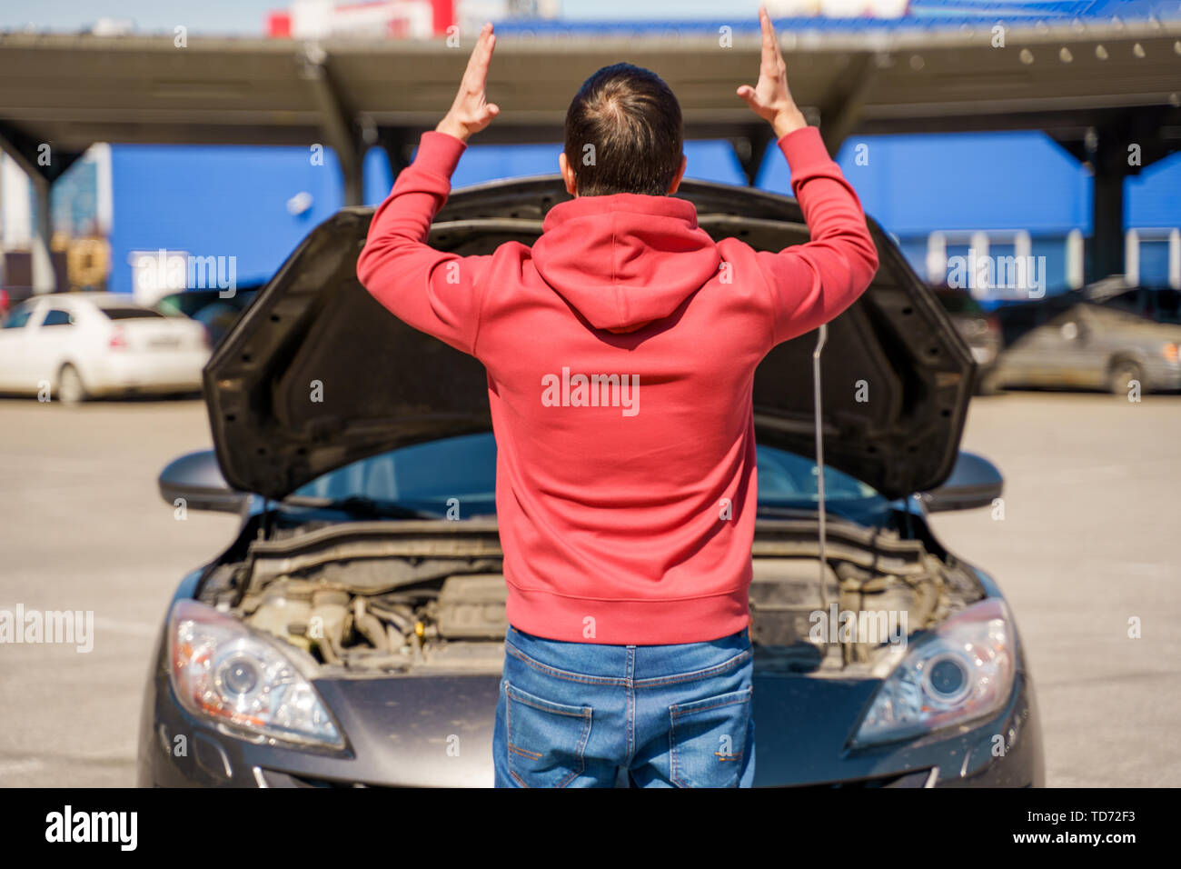 Image on back of man next to open hood of broken car in daytime Stock ...