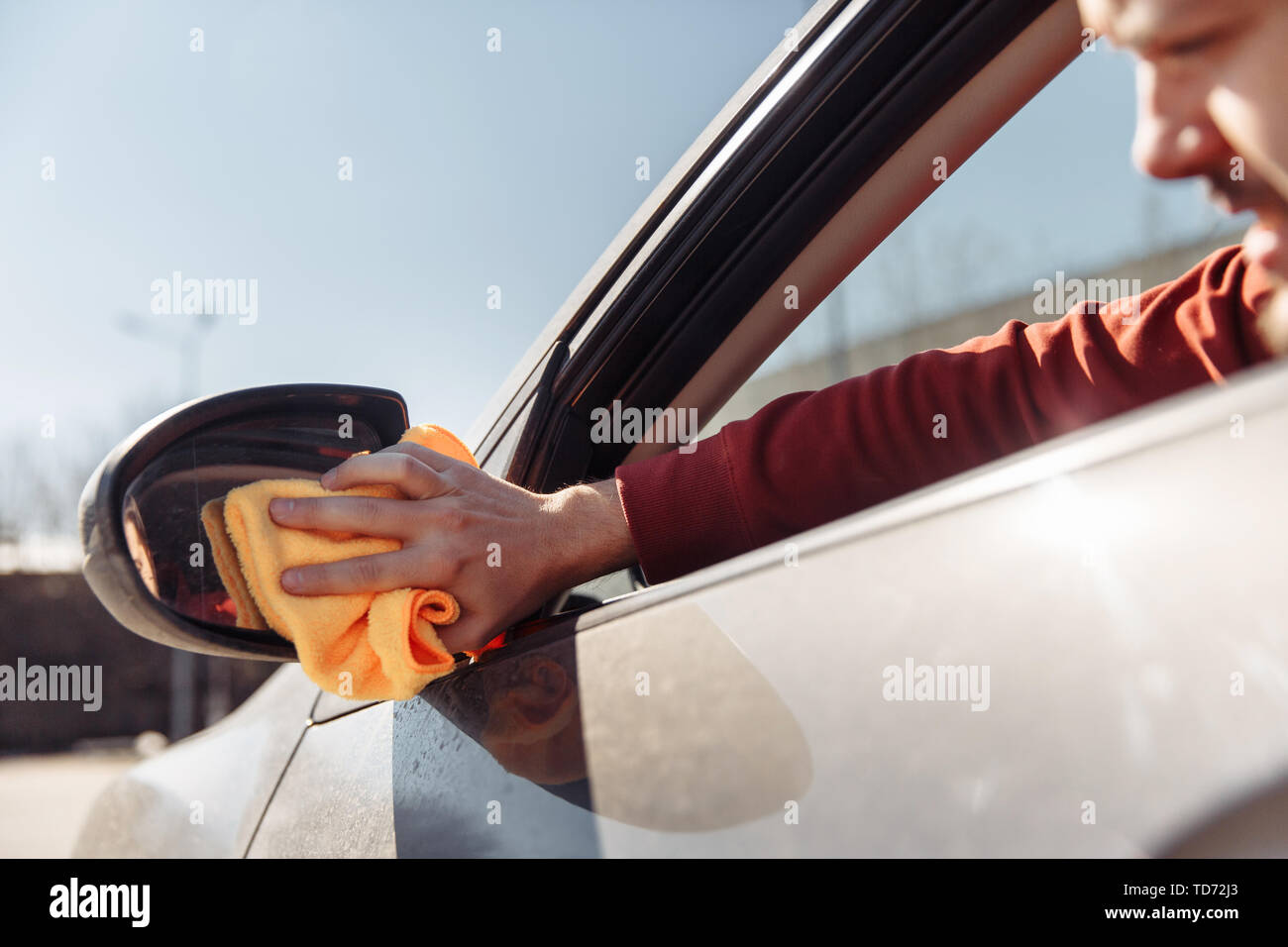 Photo of man with orange rag washing distant-looking car mirror Stock ...