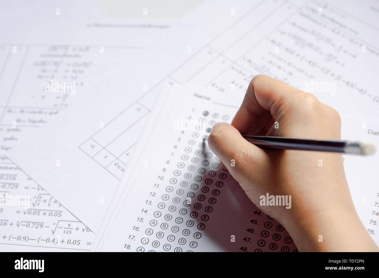 Students hand holding pencil writing selected choice on answer sheets ...