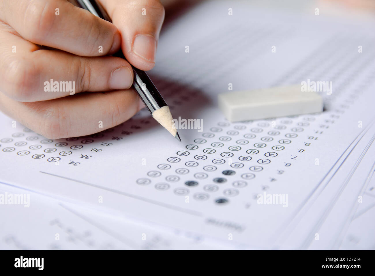 Students hand holding pencil writing selected choice on answer sheets ...