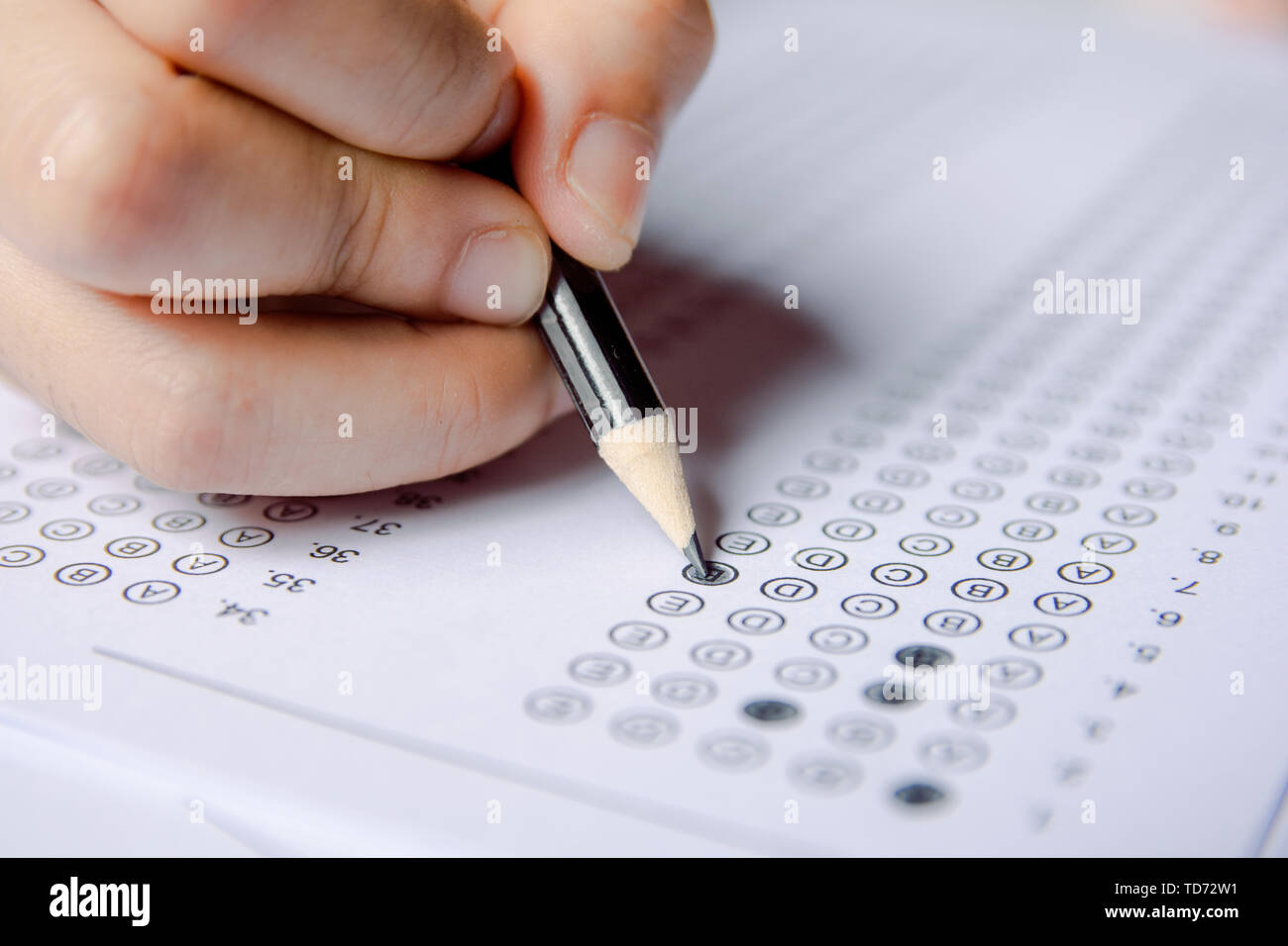 Students hand holding pencil writing selected choice on answer sheets ...