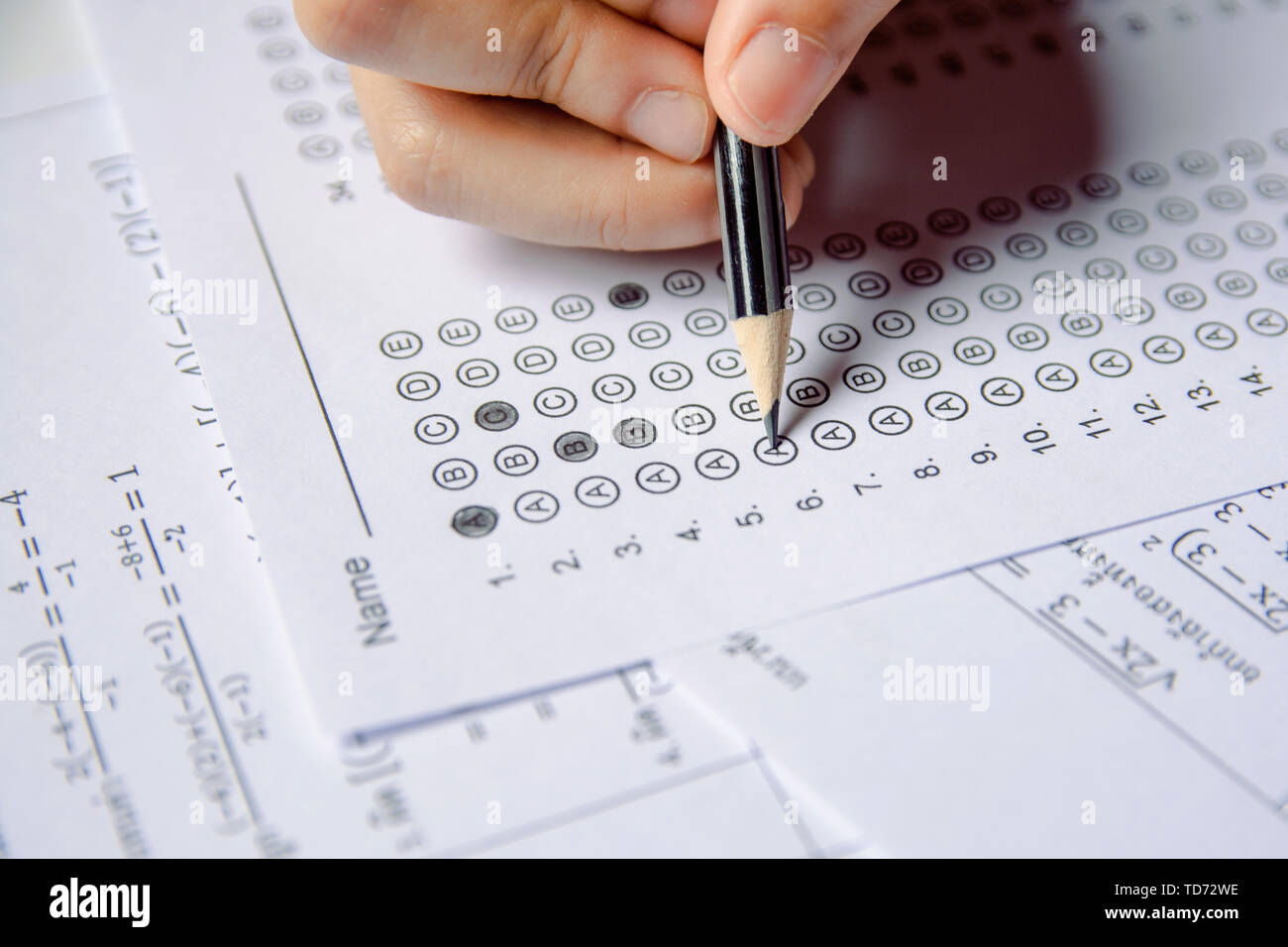 Students hand holding pencil writing selected choice on answer sheets ...