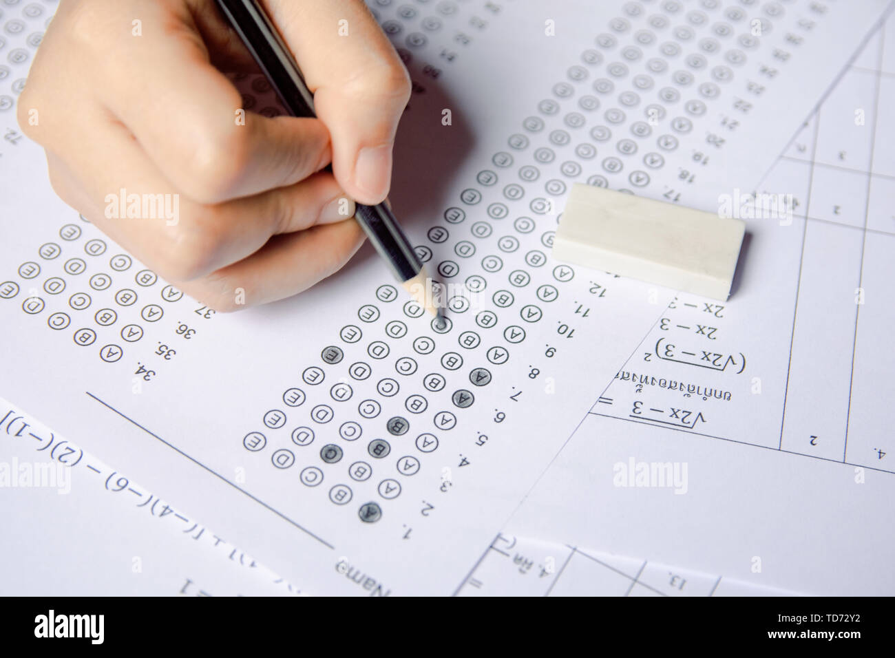 Students hand holding pencil writing selected choice on answer sheets ...