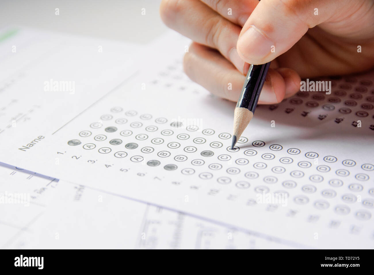 Students hand holding pencil writing selected choice on answer sheets ...