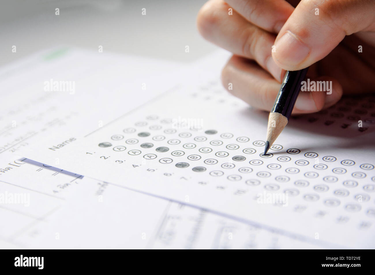 Students hand holding pencil writing selected choice on answer sheets ...