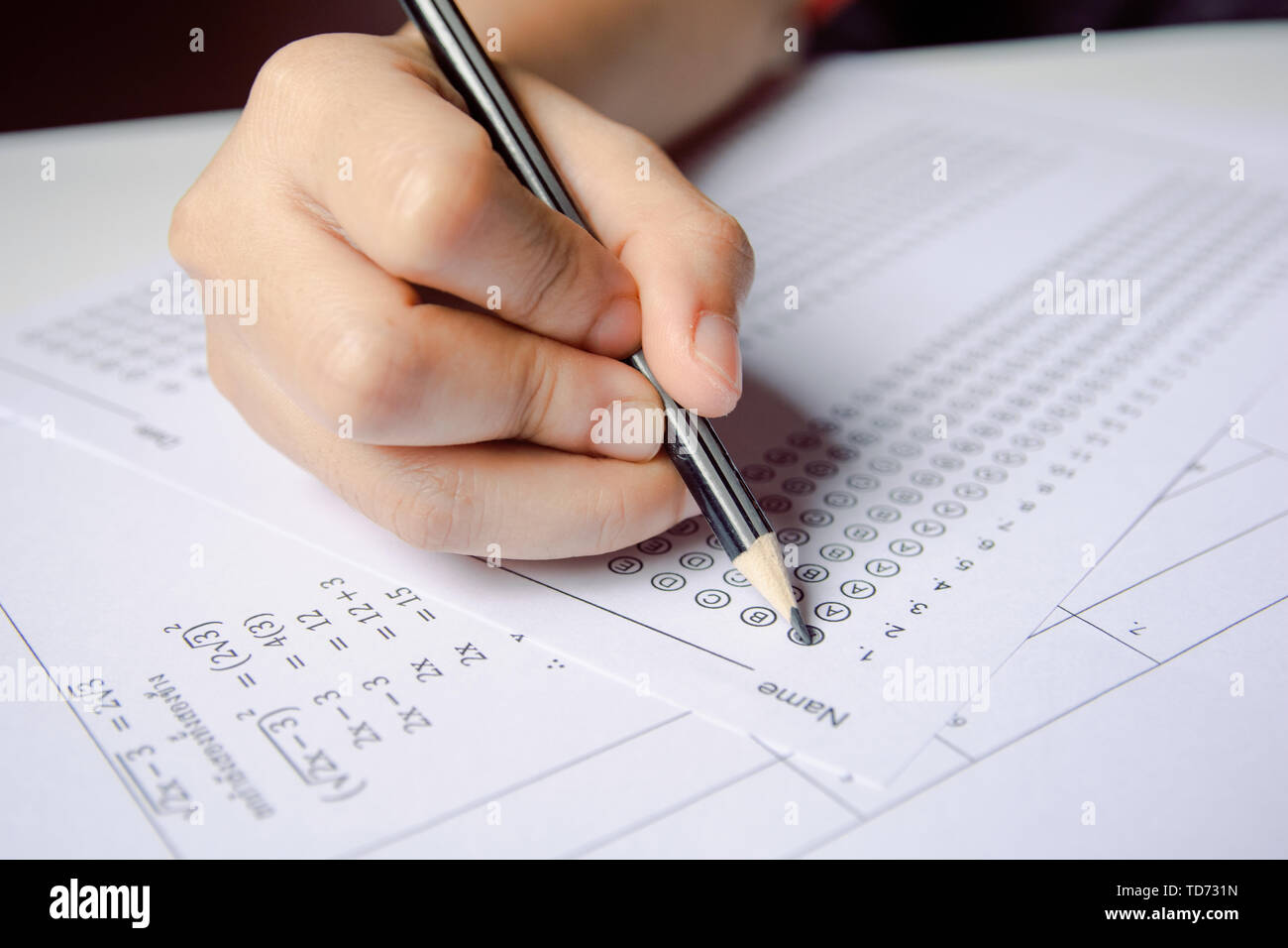 Students hand holding pencil writing selected choice on answer sheets ...