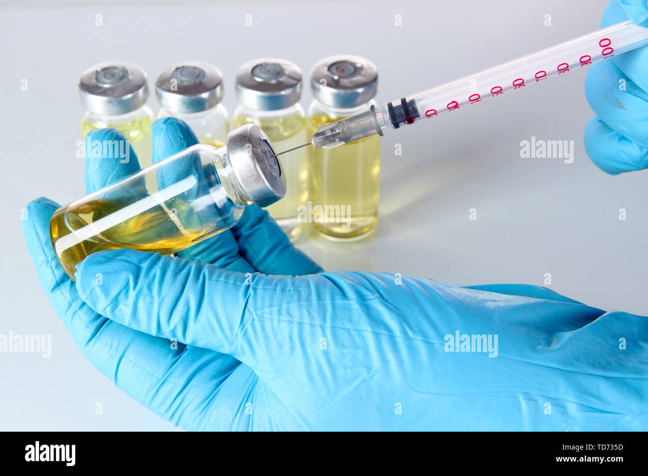 Medical bottles and syringe in hand on gray background Stock Photo - Alamy