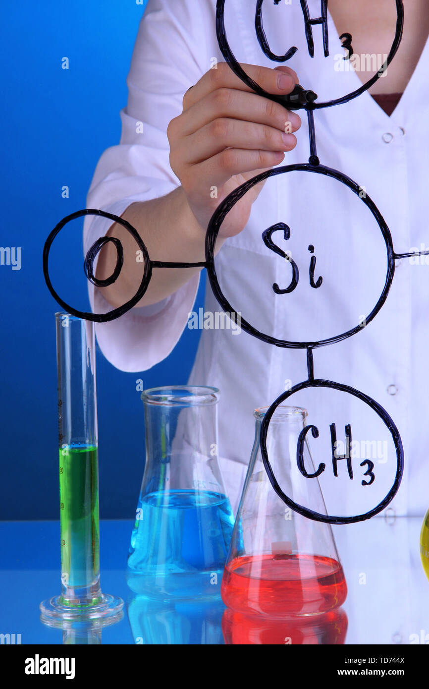 Chemist woman writing formulas on glass on blue background Stock Photo ...