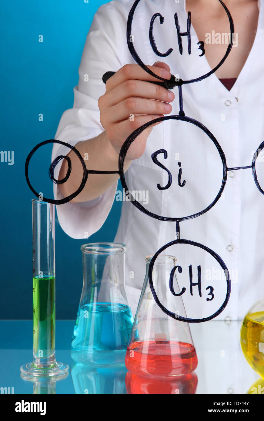 Chemist woman writing formulas on glass on blue background Stock Photo ...