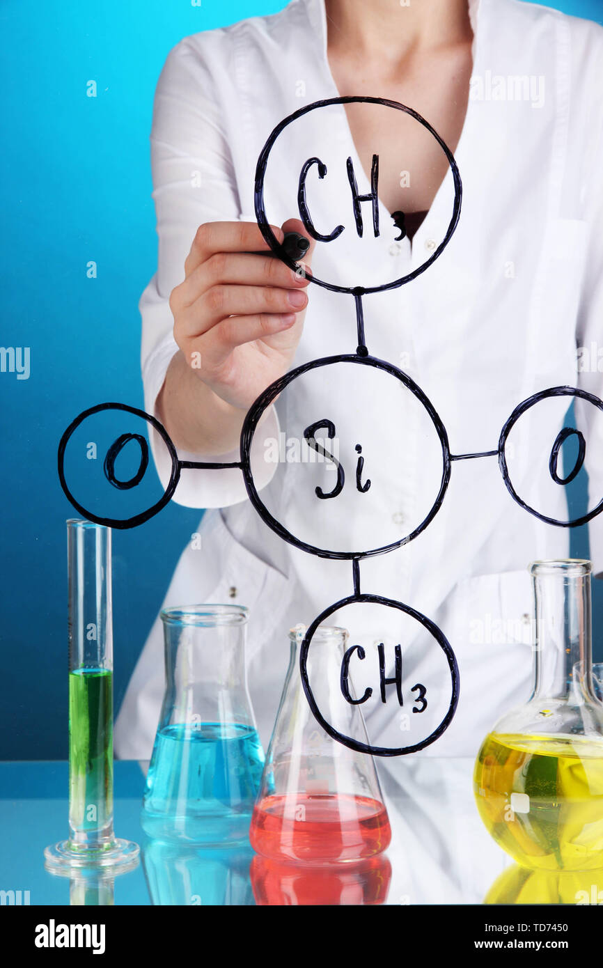 Chemist woman writing formulas on glass on blue background Stock Photo ...