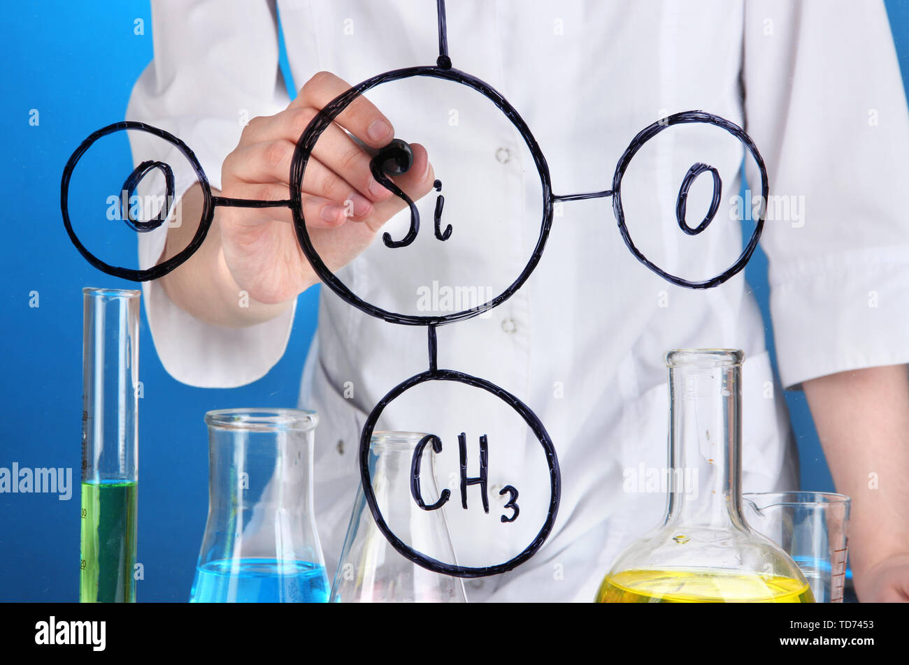 Chemist woman writing formulas on glass on blue background Stock Photo ...
