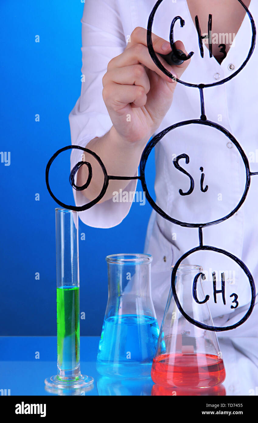 Chemist woman writing formulas on glass on blue background Stock Photo ...