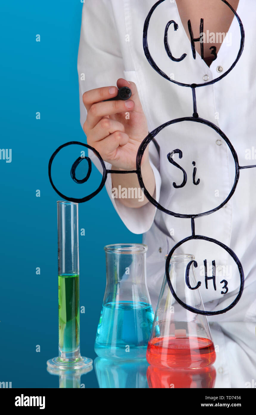 Chemist woman writing formulas on glass on blue background Stock Photo ...