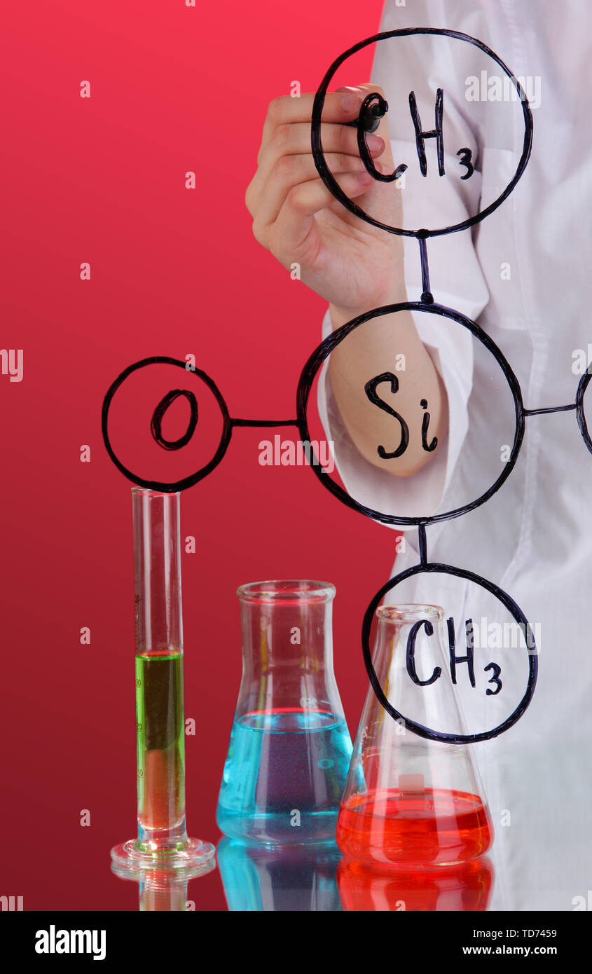 Chemist woman writing formulas on glass on red background Stock Photo ...