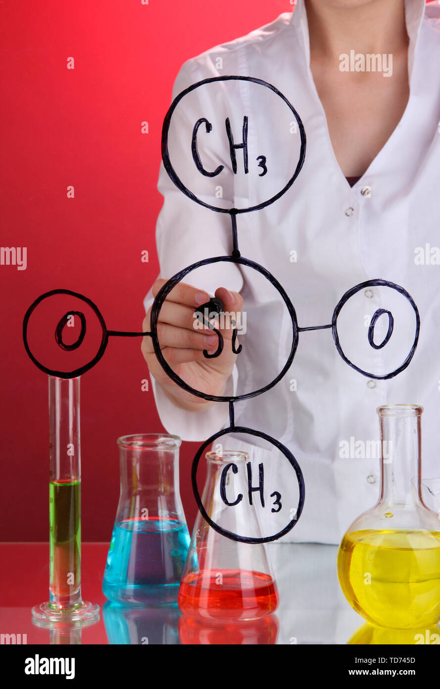 Chemist woman writing formulas on glass on red background Stock Photo ...