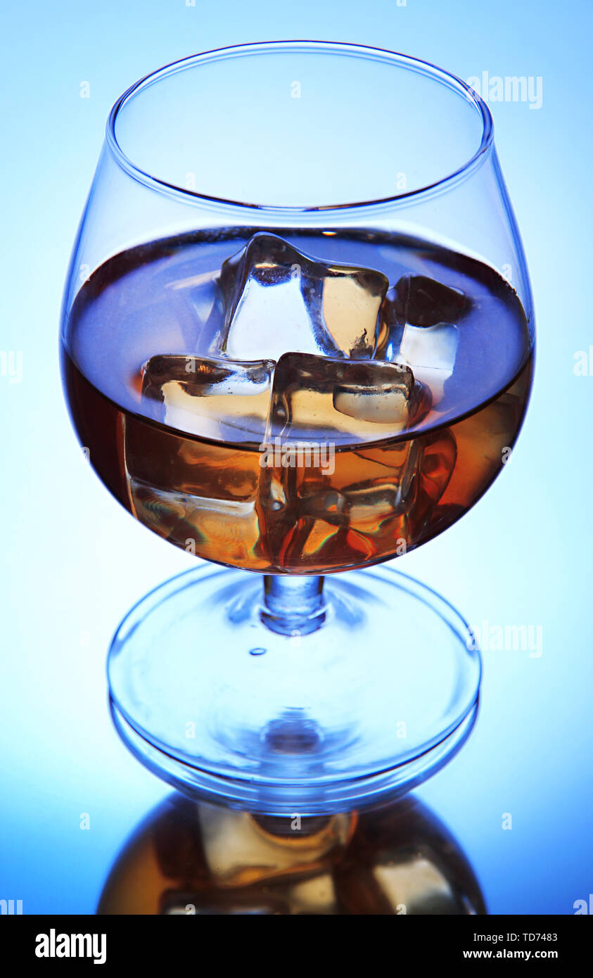 Brandy glass with ice on blue background Stock Photo - Alamy