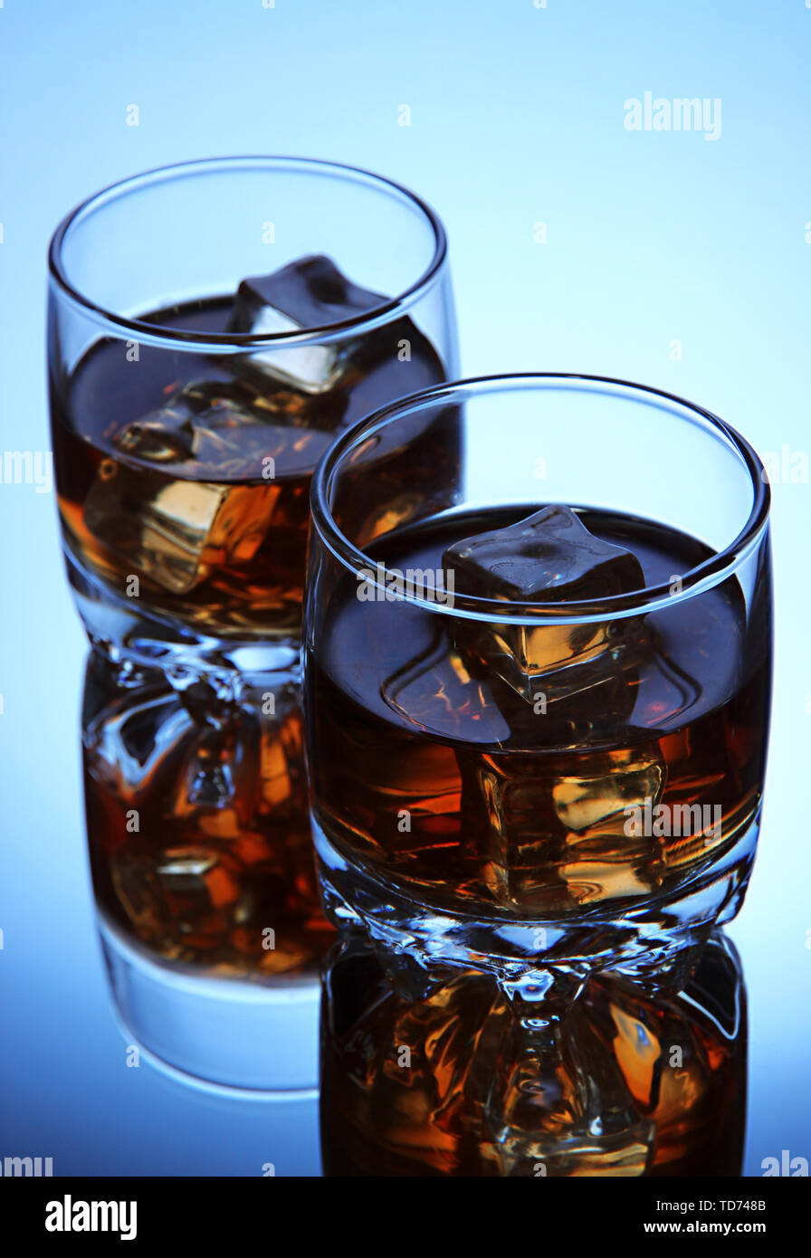 Brandy glasses with ice on blue background Stock Photo - Alamy