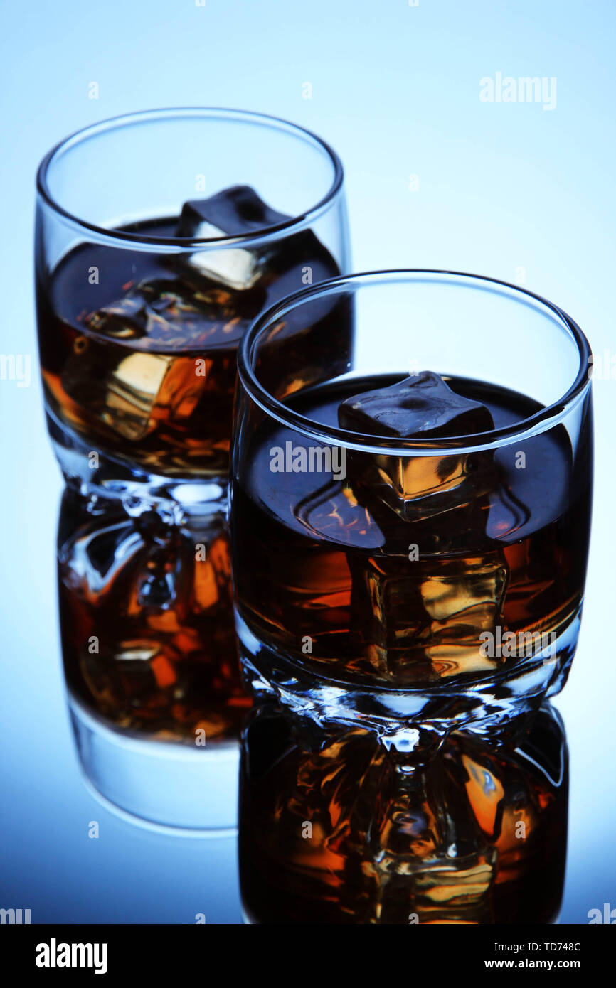 Brandy glasses with ice on blue background Stock Photo - Alamy
