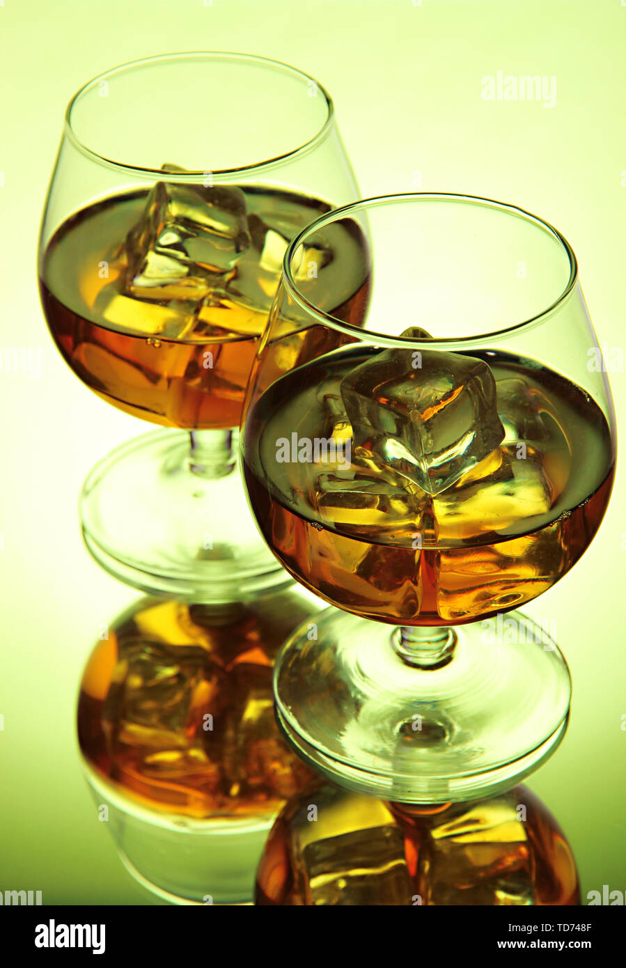 Brandy glasses with ice on green background Stock Photo - Alamy