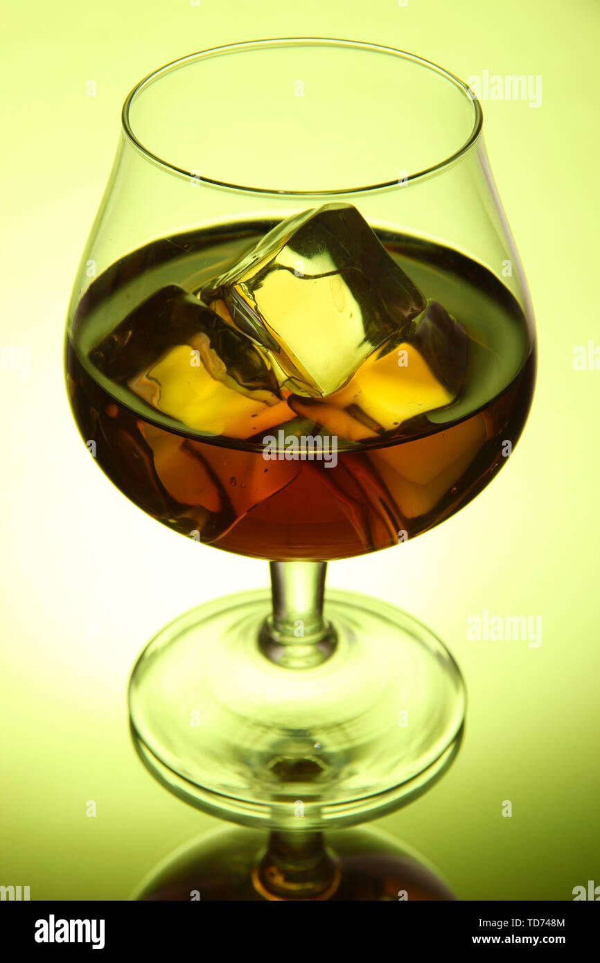 Brandy glass with ice on green background Stock Photo - Alamy