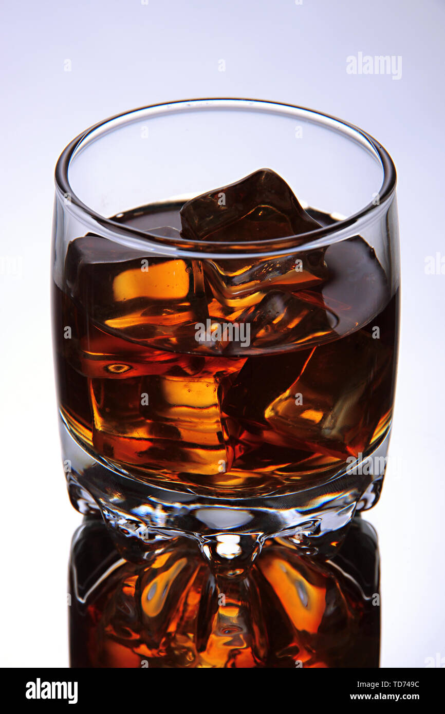 Brandy glass with ice on grey background Stock Photo - Alamy