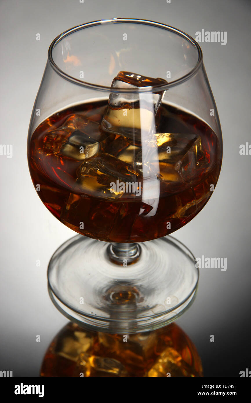 Brandy glass with ice on grey background Stock Photo - Alamy