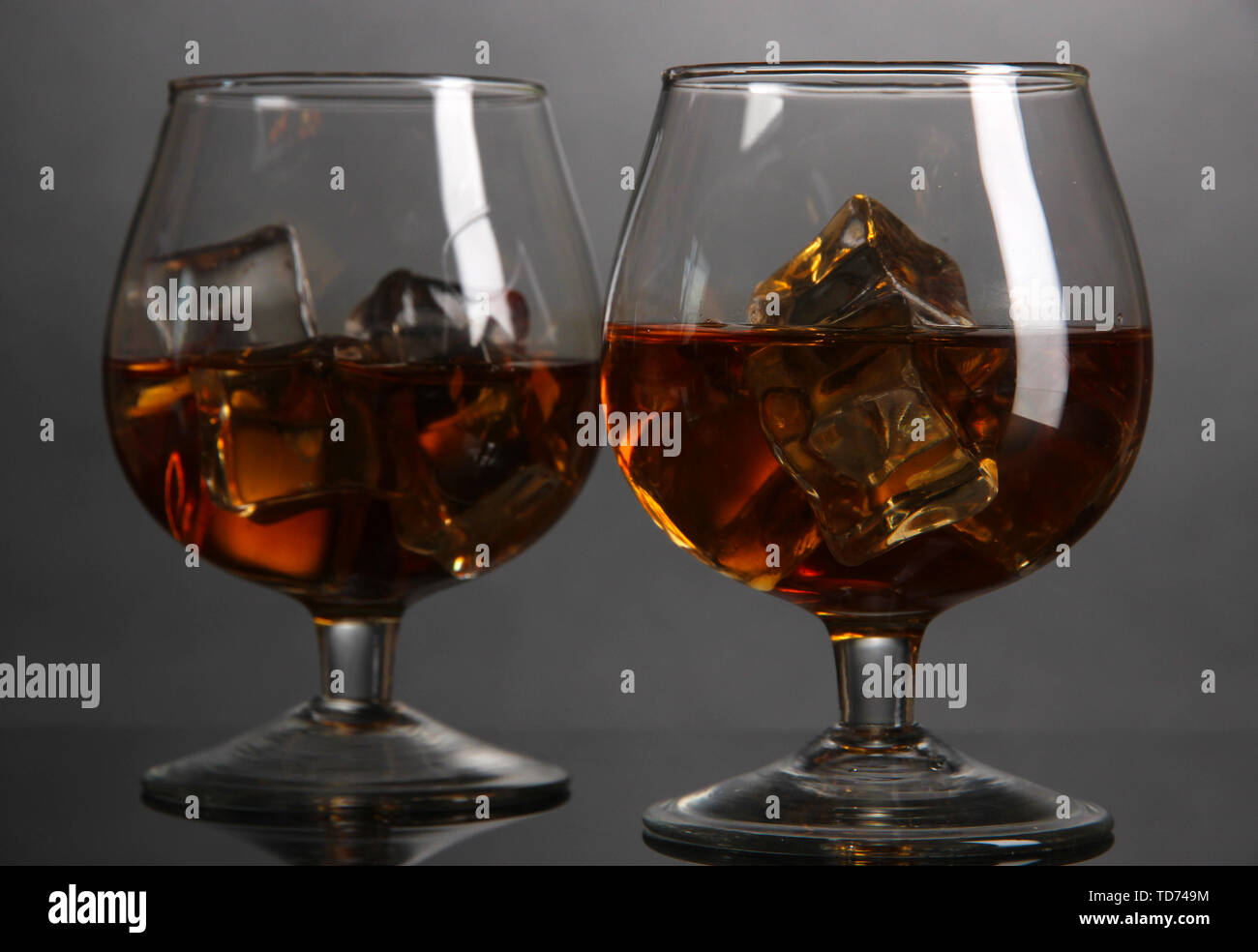 Brandy glasses with ice on grey background Stock Photo - Alamy