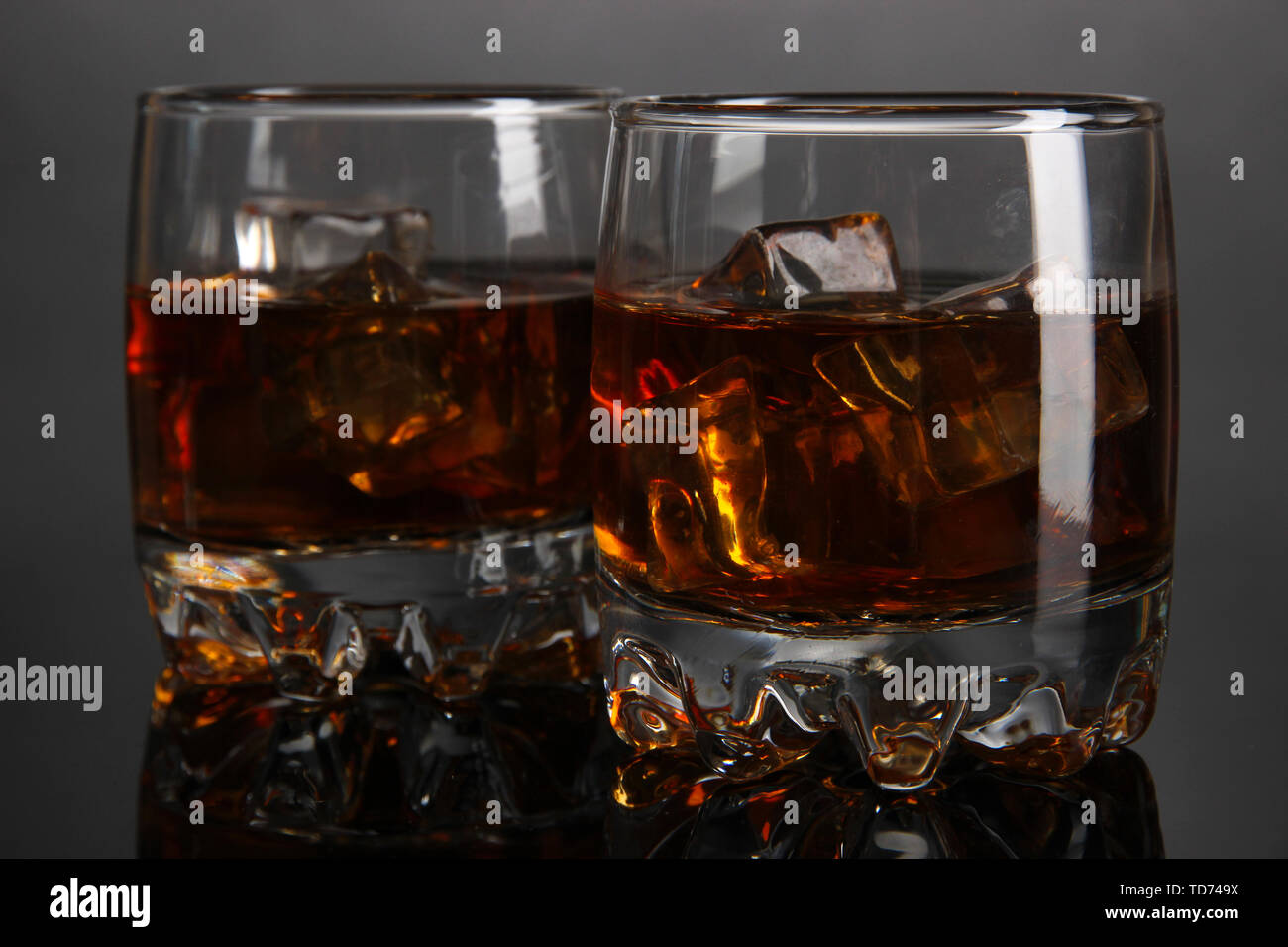 Brandy glasses with ice on grey background Stock Photo - Alamy