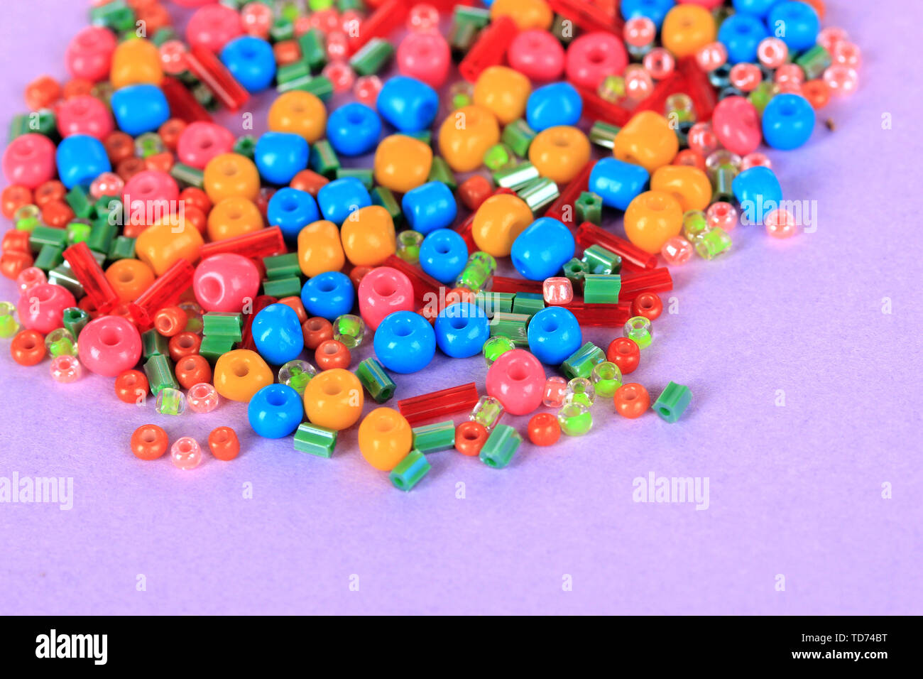 Different colorful beads on purple background Stock Photo - Alamy