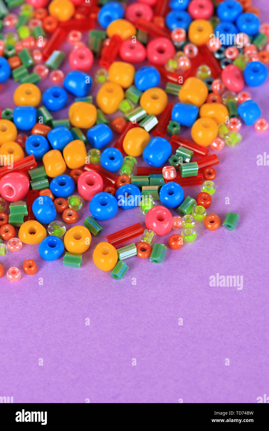 Different colorful beads on purple background Stock Photo - Alamy