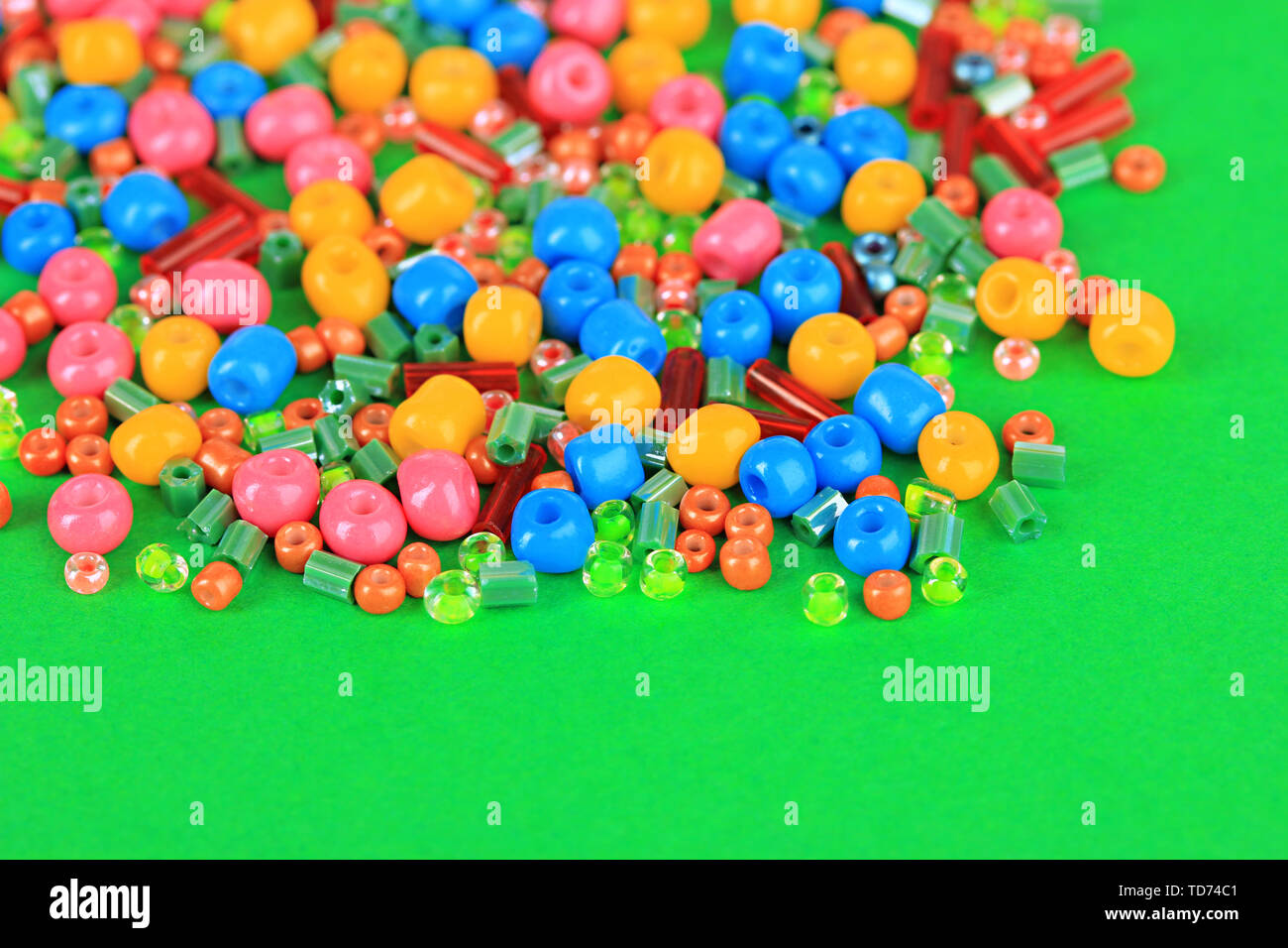 Different colorful beads on green background Stock Photo - Alamy