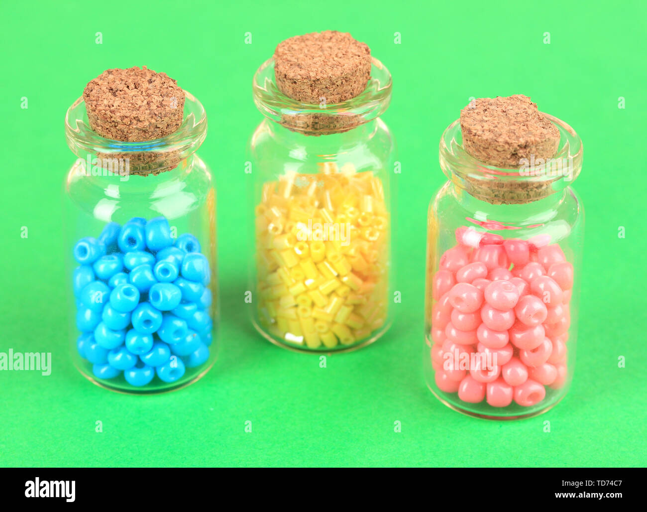 Different colorful beads in bottles on green background Stock Photo - Alamy